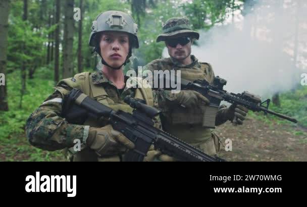 Squad of soldiers patrolling across the forest area, team with male and ...