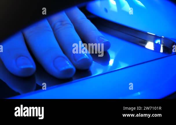 Closeup of female blue nails and skin because of blue light of led lamp ...