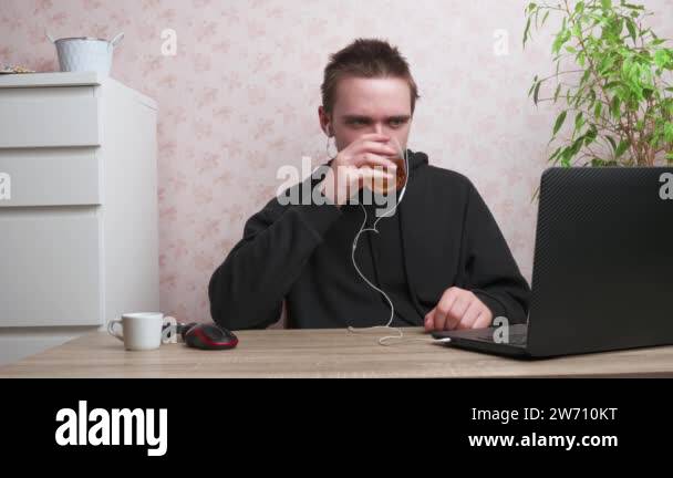Young guy sitting at a computer watching a scary movie, sitting at a ...