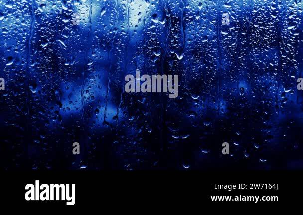 Rainy background neon blue color, drops flow down the glass, copy space ...
