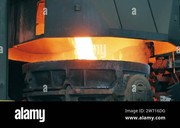 Melted metal is pouring into a factory tank. Metallurgy concept. Molten ...