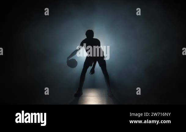Silhouette of basketball player dribbles ball practicing skills in a ...