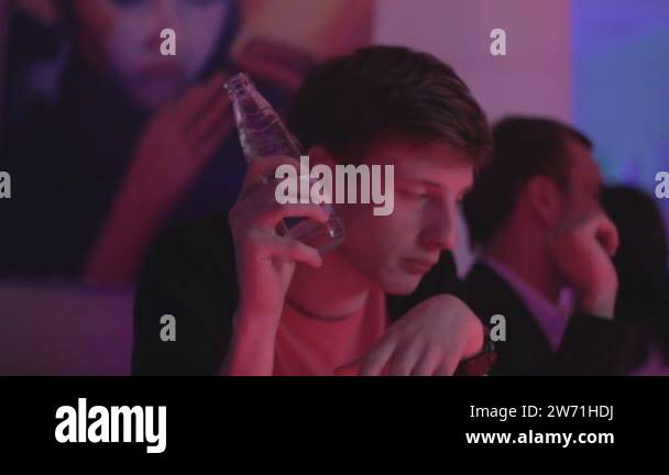 Party in the night club. Drunk guy holding bottle, people drinking at ...