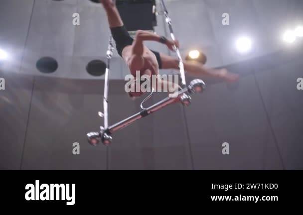 Acrobatic man at the circus arena - hanging upside down on the rotating ...