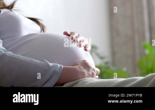 4k Side view Pregnant expectant mother caressing her belly. Woman hands ...