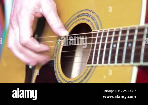 A man's hand on the fretboard of a guitar runs his fingers through the ...
