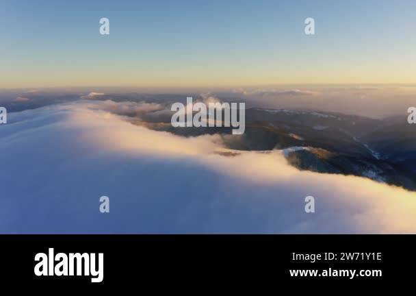 Cloud waves gently and slowly flow over the tops of snow-capped ...