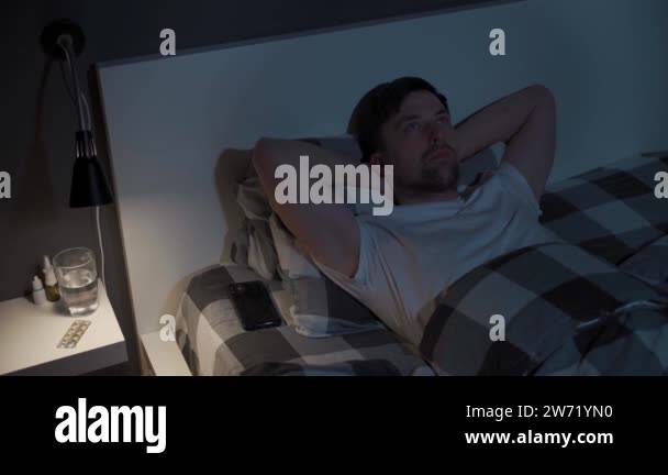 Lonely man cannot sleep in bed at night with eyes wide open, staring at ...
