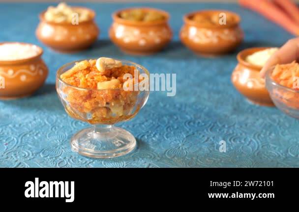 Bowl of freshly grated carrots kept with Gajar Ka Halwa garnished with ...