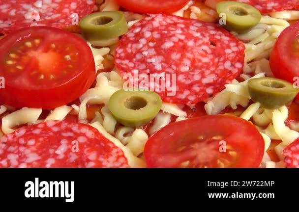 Spinning pizza with mozzarella cheese, olives, tomatoes, tomato sauce ...