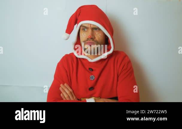 A young handsome guy in a red santaclaus carnival costume happily ...