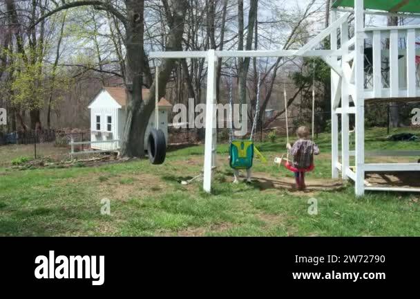 Brother and sister swinging and playing together in their backyard ...