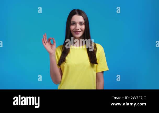 Pretty woman showing ok, okay sign over blue studio background ...
