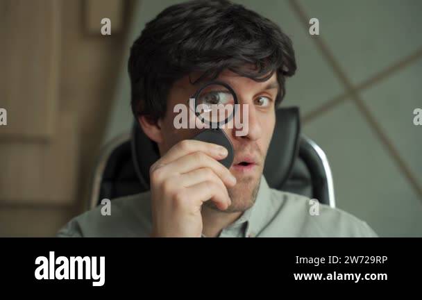 Man see through magnifying glass. Male taking a magnifying glass and ...