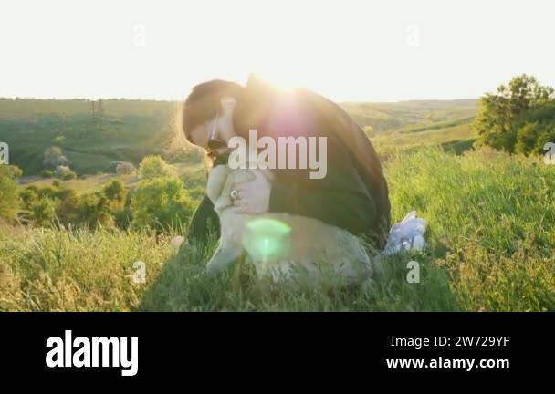 female owner hugs and kiss her dog on sunset. Pug and woman sit in ...