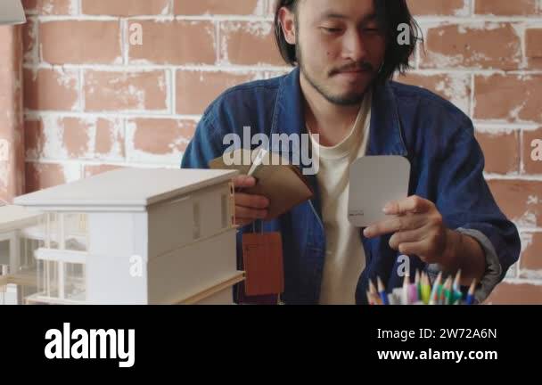 Smart asian male Architect working with his architectural model ...