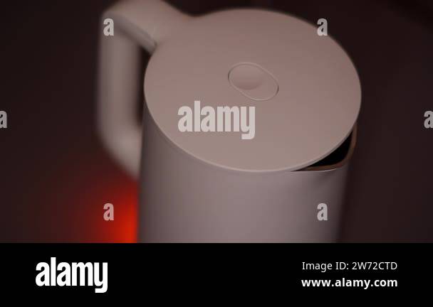 Electric kettle top view, power button is lit, dark background, camera ...