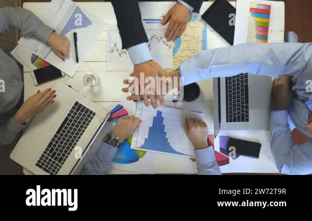 Top view to hands of four business people celebrating achievement. Group of employers stacked ...