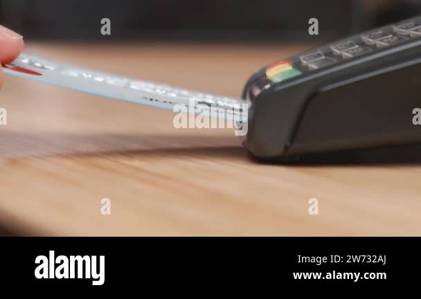 Close up man hand inserts credit card into the pos terminal and enters ...