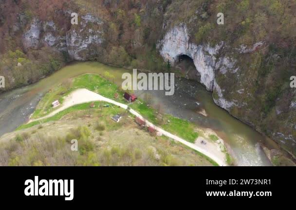 Aerial above view of a wild mountain river meander and a gigantic cave ...