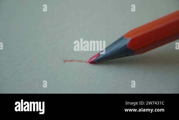 Graphite orange color pencil draws a straight line on a white ...