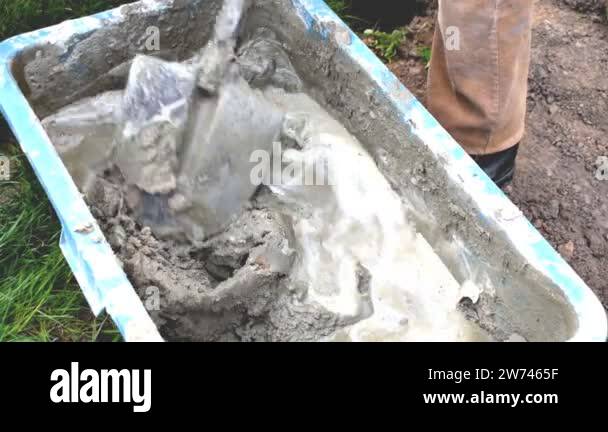 Close up worker mans hands in gloves mixing, stirring cement slurry ...