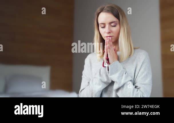 portrait young girl or woman sincerely praying on rosary at home ...
