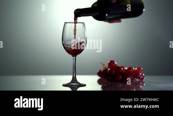 Red wine forms beautiful wave. Wine pouring in wine glass over white ...