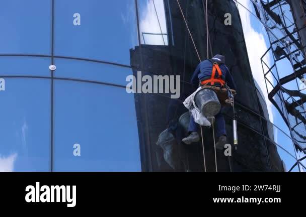 Window washers on glass building facade. Industrial climbers wash ...