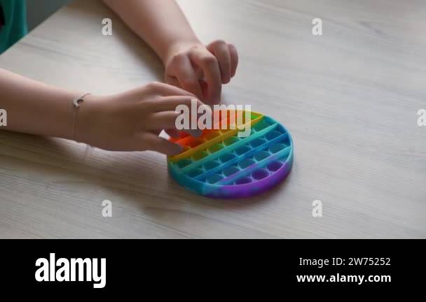 Close up shot of kids fingers on pop it fidget toy. Instrument for ...