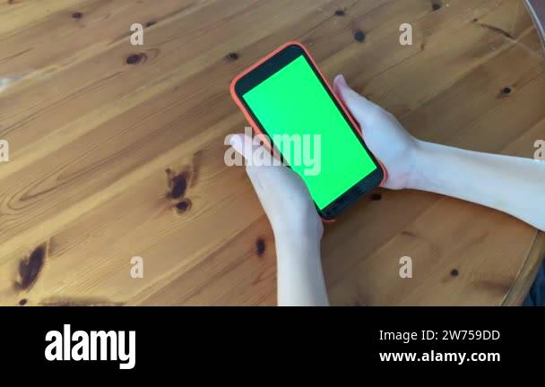 Young teenager boy hands using green screen smartphone sitting on the ...