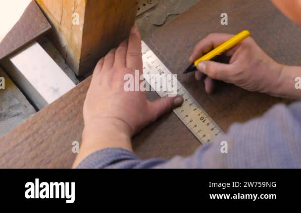 Flooring installation a terrace. Carpenter draws a cutting line on wood ...