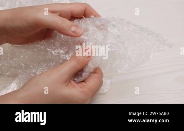 Woman presses a bubble wrap. Female hands burst air bubbles on a bubble ...