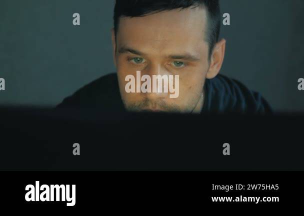 A young IT specialist works remotely on his laptop.Young attractive guy working on his laptop ...