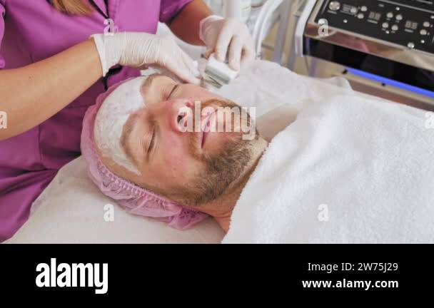 Middle aged man receiving facial micro current treatment at spa salon ...
