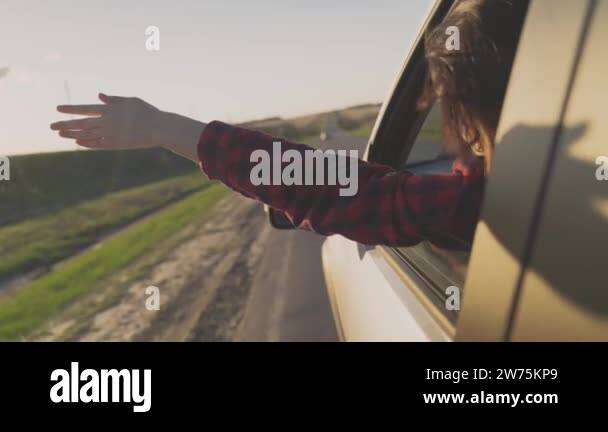 The girl travels with her hand out the car window and catching the wind ...