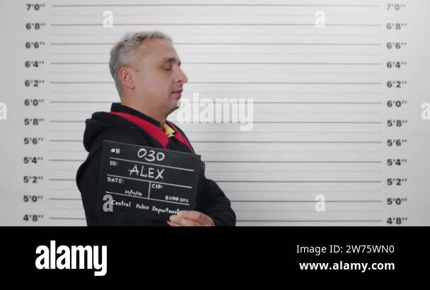 Side profile mugshot of male criminal holding sign while being ...