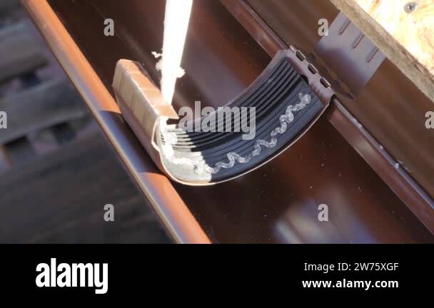 Placing the silicone on the gutter connector from the construction gun ...