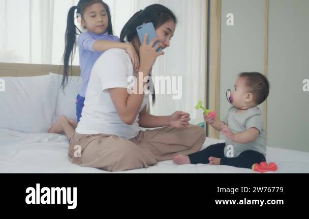 Young asian mother talking phone and playing with baby girl together on ...