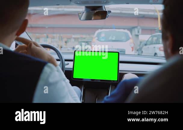 Back view of two men sitting in a car and talking while waiting at a ...