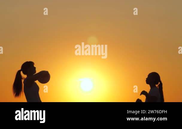 Mom and daughter are playing and throwing ball to each other under the ...