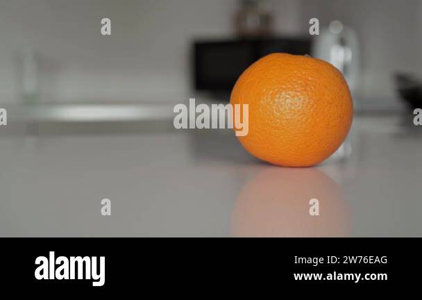 Horizontal pan to the right footage of one single orange on the white ...