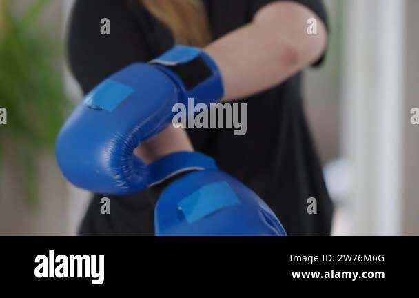 Chubby unrecognizable woman putting on boxing gloves and hitting palms ...