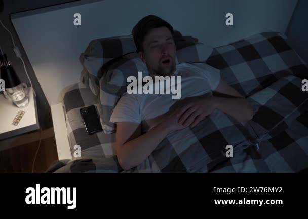 Lonely man cannot sleep in bed at night with eyes wide open, staring at ...