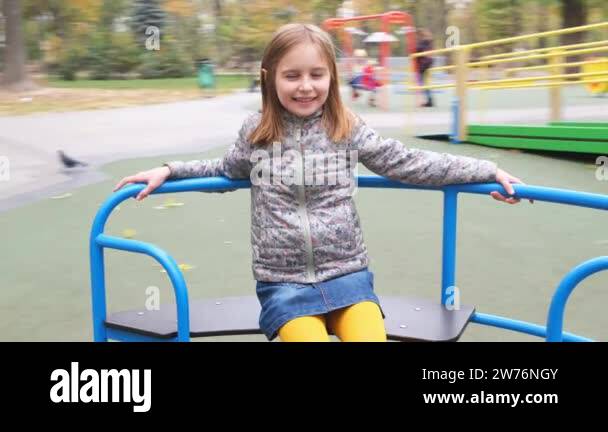 Little girl on roundabout in city park Stock Video Footage - Alamy
