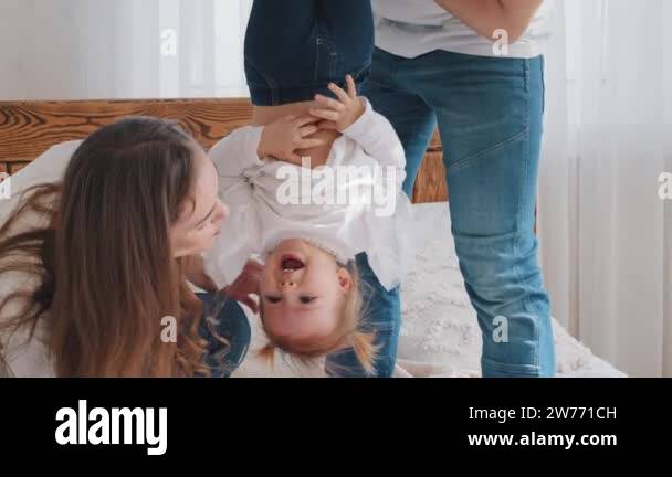 Close-up caring strong father holding little baby daughter toddler by legs upside down child ...