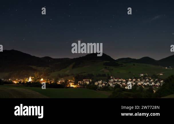 Starry night sky with stars over rural village with traffic and street ...