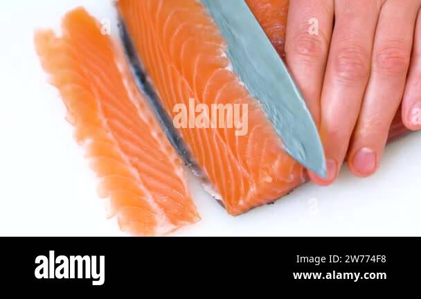 Male chef cuts, slicing a fresh salmon fillet in the sushi bar ...