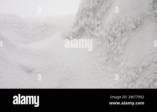 Snow layers accumulating on rock in hard stormy cold weather in winter ...