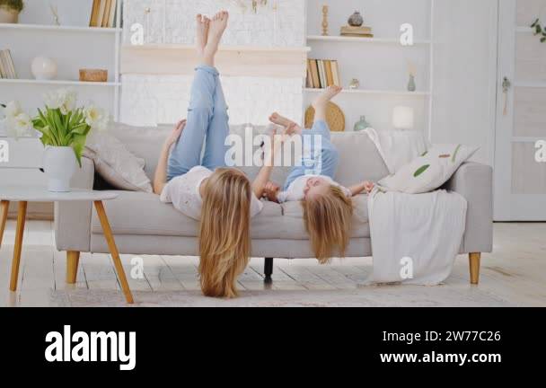 Mother and small daughter caucasian family lie on sofa in living room ...